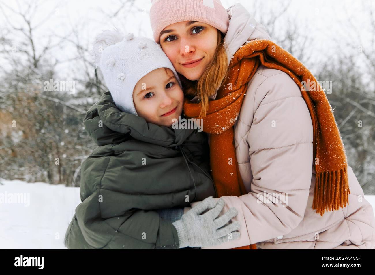 Lovely happy family mother and little girl daughter having fun on snowy ...