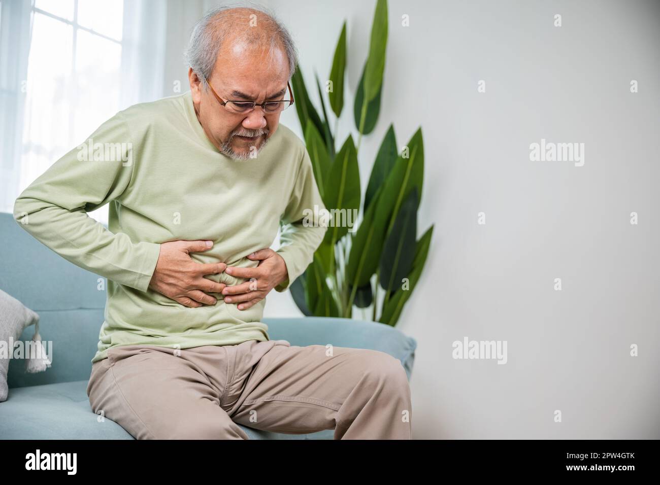 Elderly Asian old man sitting on sofa having stomachache, old age ...