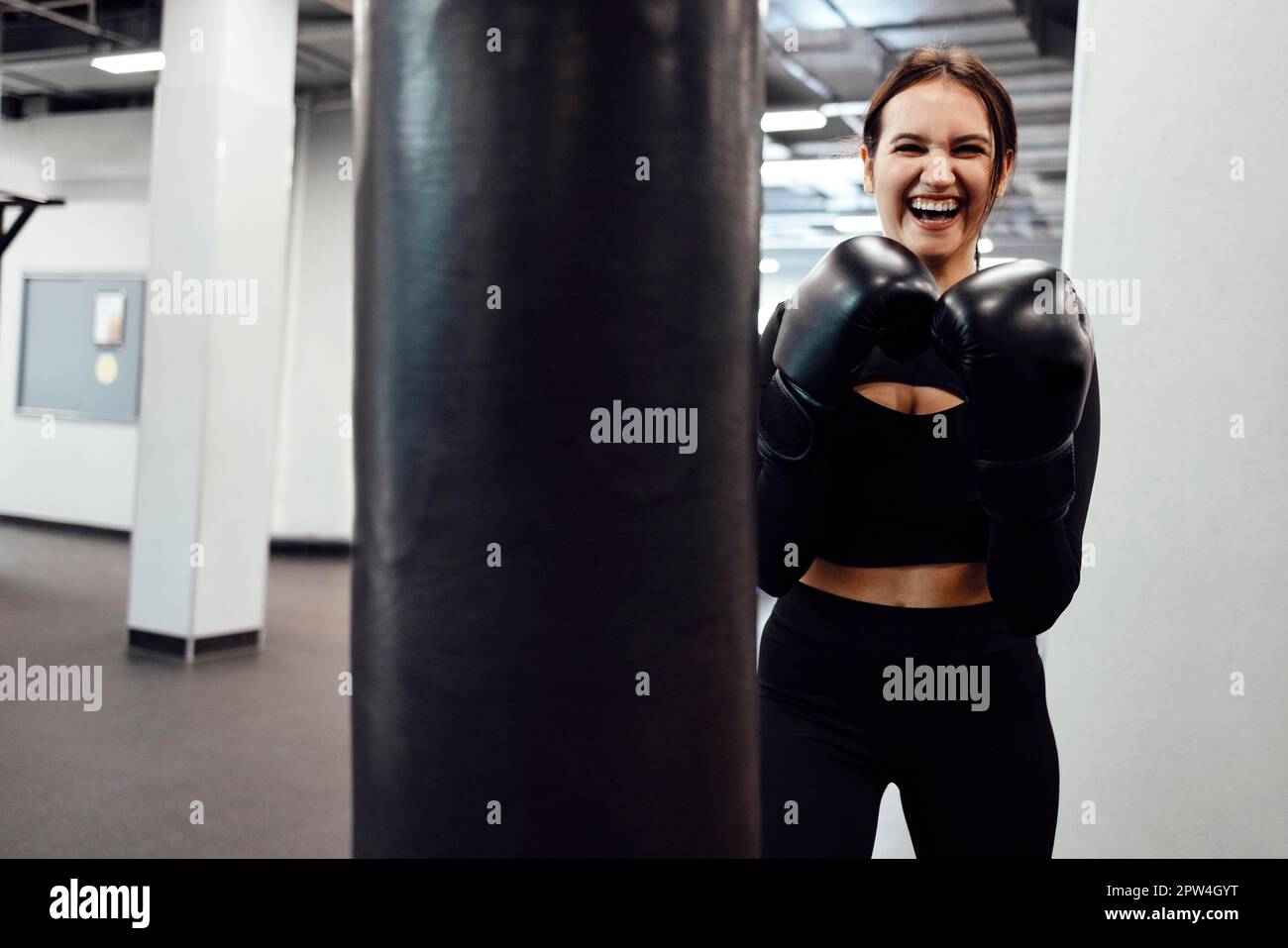 Strong Latin Boxing Woman Jump Kick To Huge Punching Bag At Fitness Gym