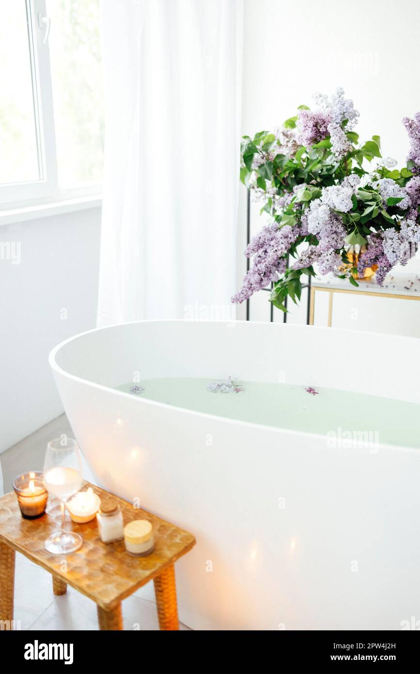 Modern bath room and spa center on the white tub wooden table. Candles ...