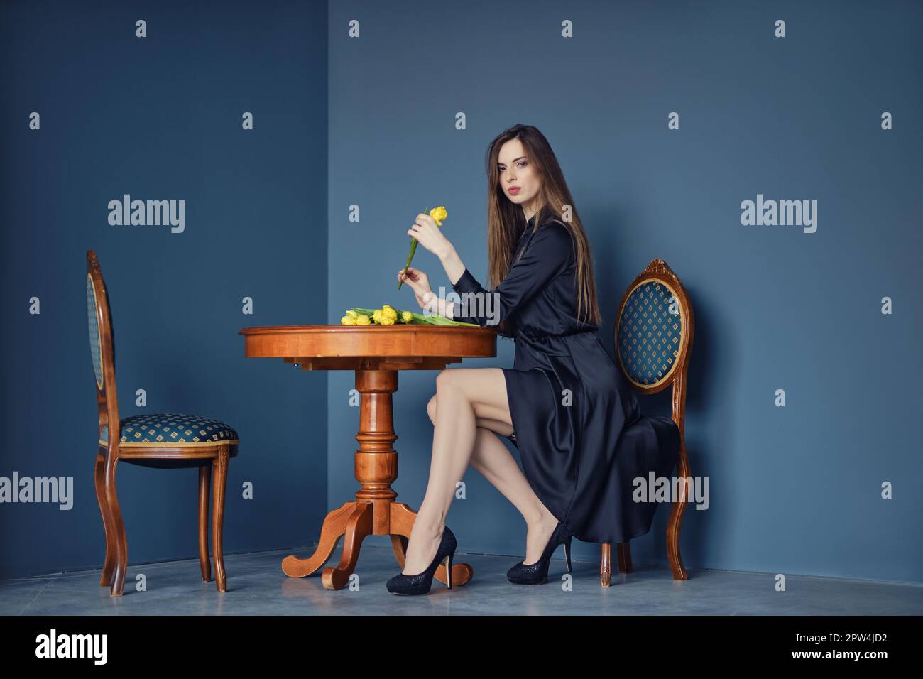 Beautiful young woman sits behind the table in victorian style with ...