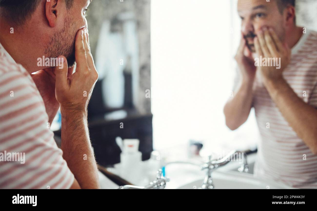 Millennial handsome man looking in mirror, applying moisturizing ...