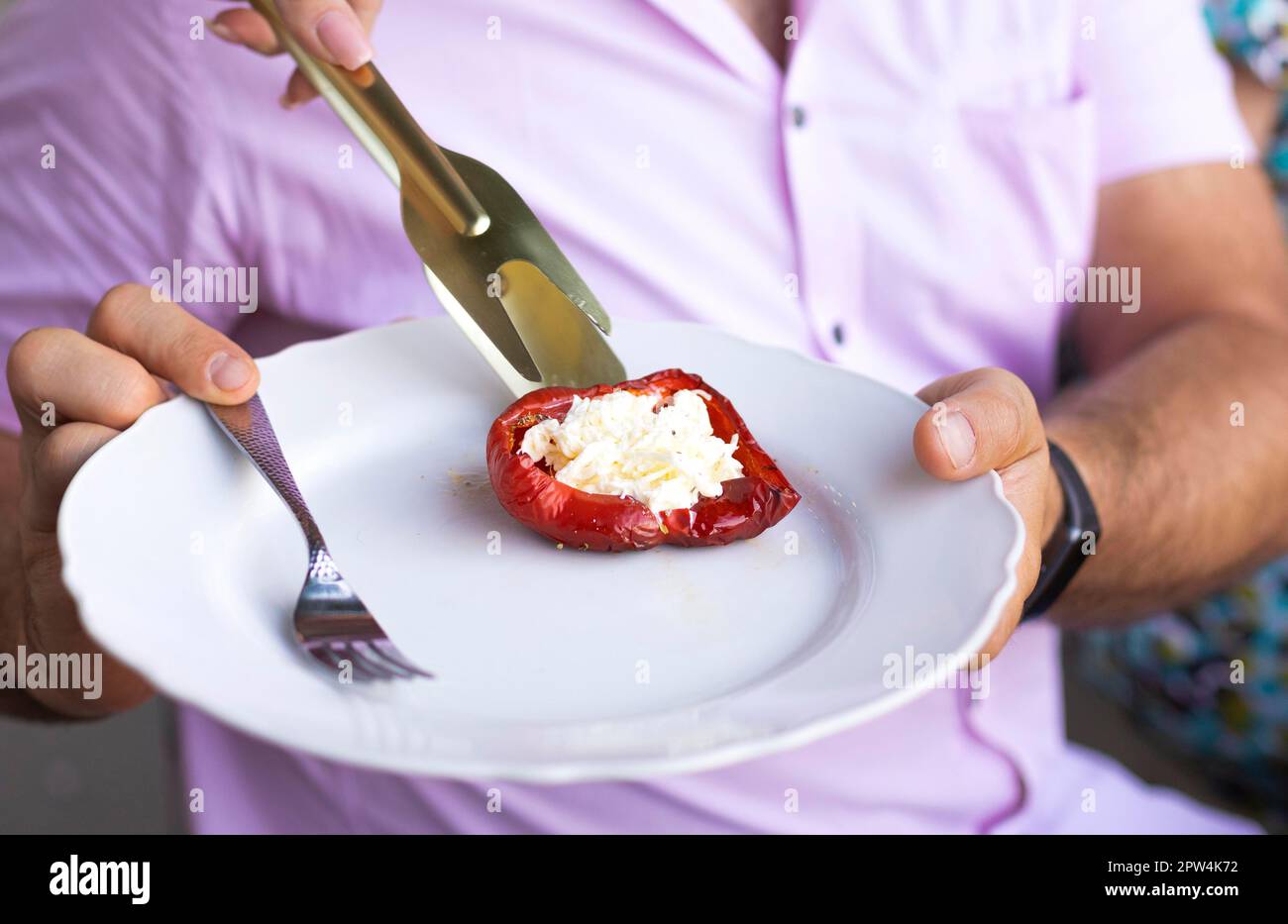 Baked red-colored bell peppers stuffed with herbs and cheese on a dish ...