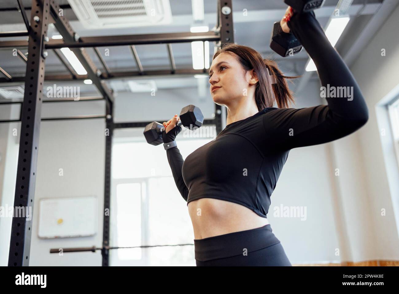 Gym woman doing push up exercises with dumbbells. Strong brunette ...