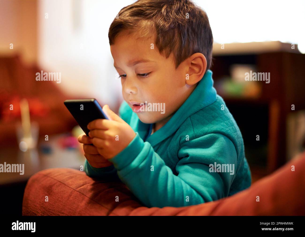 Hes riveted by that game. a little boy playing with a cellphone Stock ...