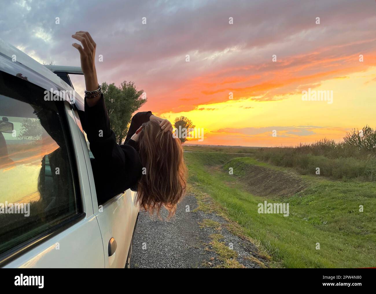 Young woman in sunglasses looks out of the window of a white car ...