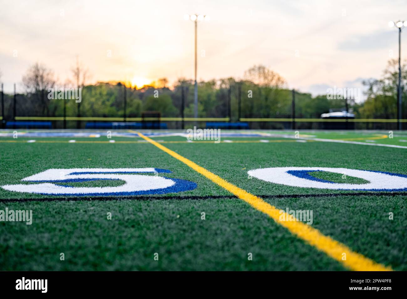Dramatic late afternoon photo of the 50 yard line on a synthetic turf ...