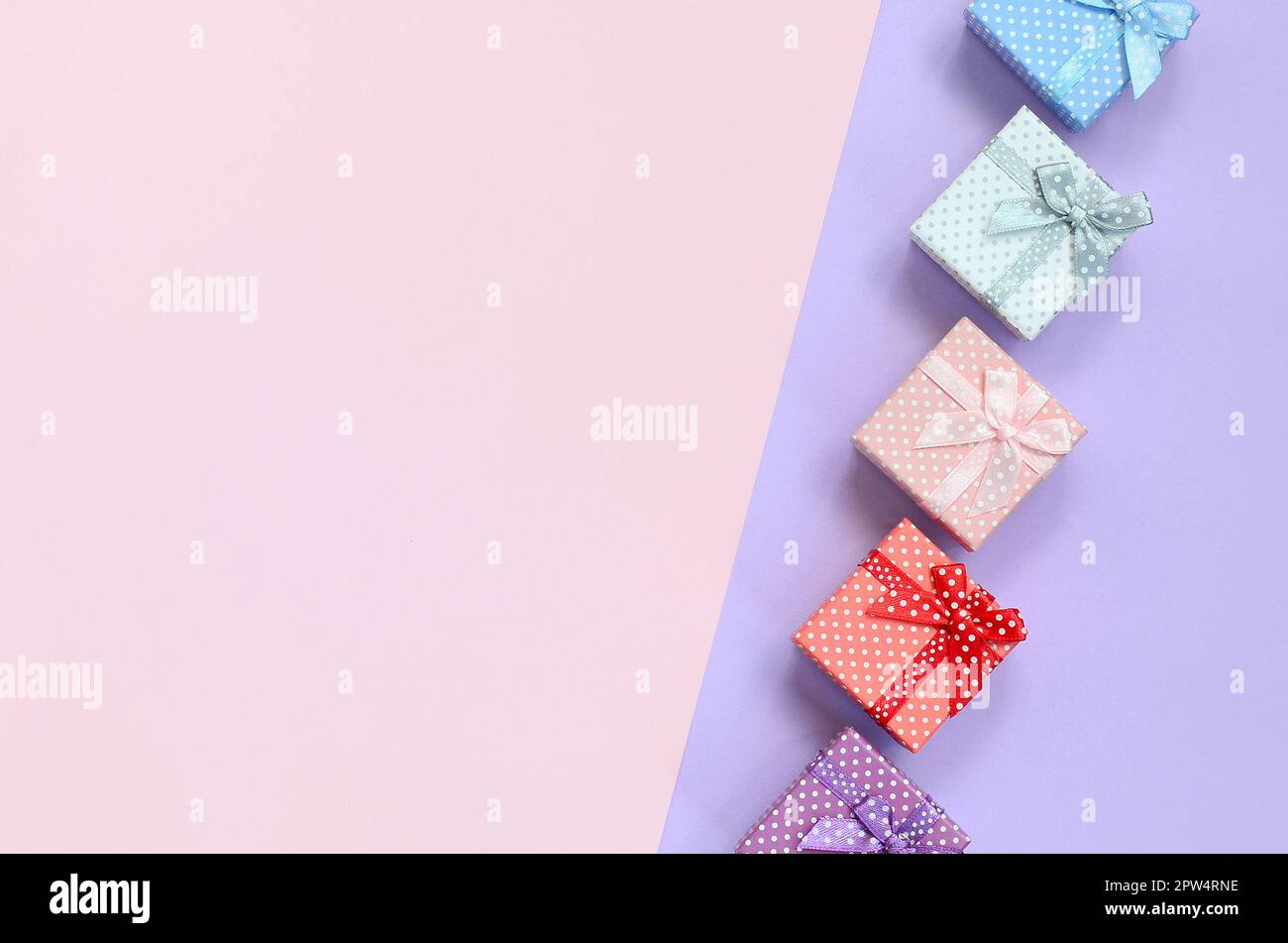 Small gift boxes of different colors with ribbons lies on a violet and ...