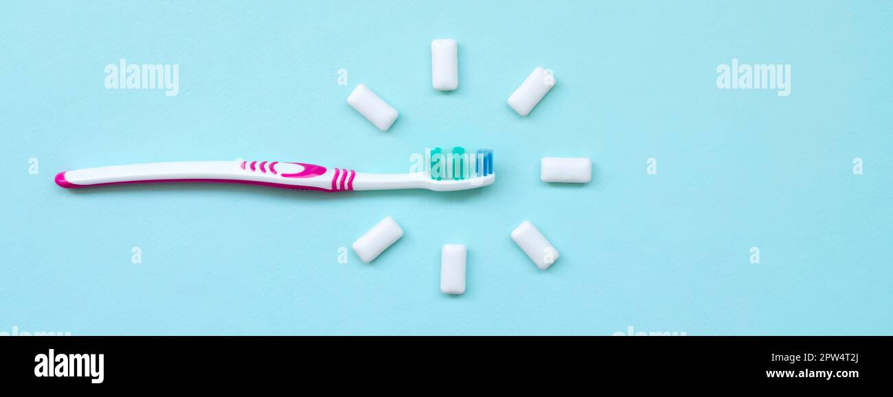 Toothbrush and chewing gums lie on a pastel blue background. Top view ...