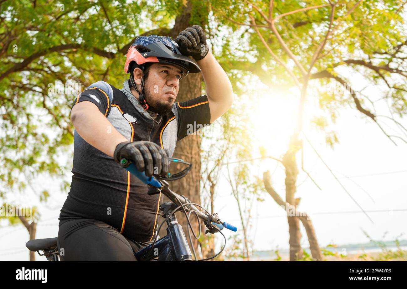 Tired cyclist while riding the bike on a road. Exhausted chubby cyclist ...