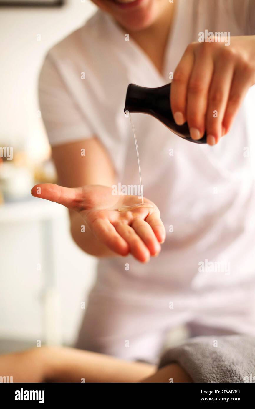 Crop faceless masseuse pouring oil on hand during relaxing massage in ...