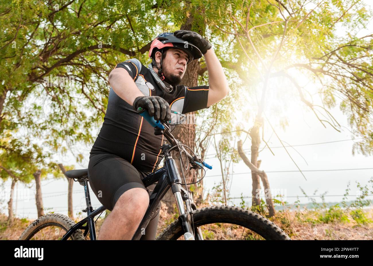 Exhausted chubby cyclist on his bike looking into the distance. Tired ...
