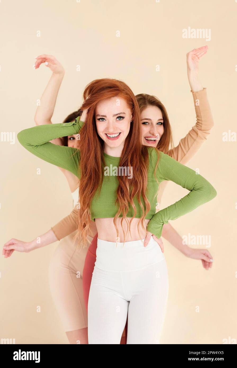 Cheerful young girlfriends smiling and looking at camera while hugging ...