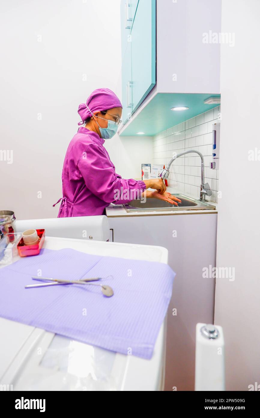 A female Asian dentist washing her hands before/after treating her ...