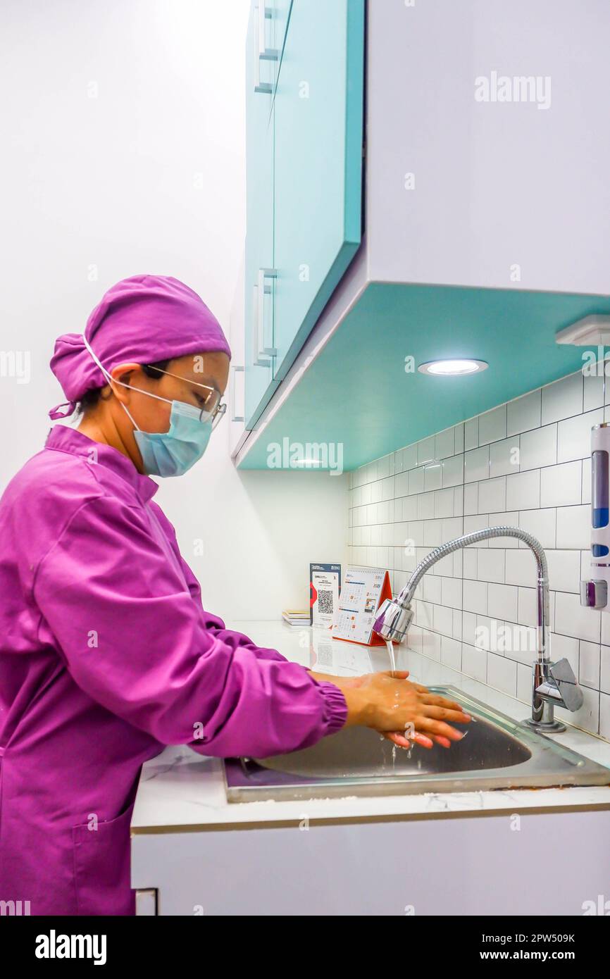 A female Asian dentist washing her hands before/after treating her ...