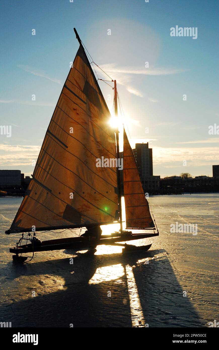 An adult man sails his ice yacht on a frozen river in winter, heading ...
