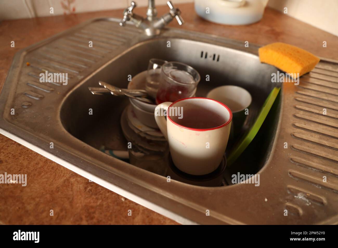 Stack of dirty dishes with food leftovers in the kitchen sink. Unwashed ...