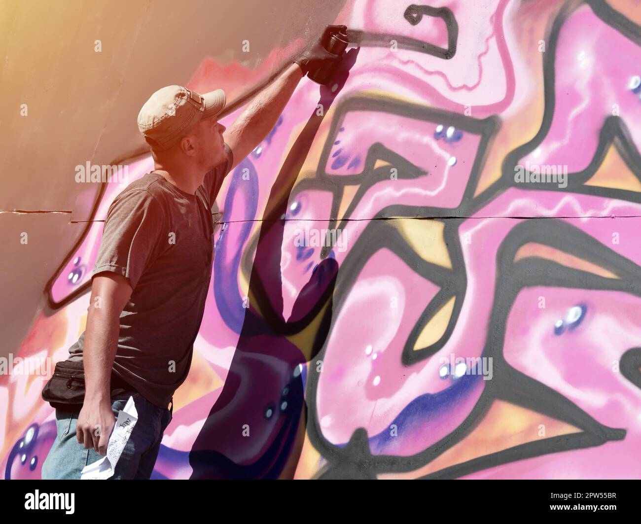 Young caucasian male graffiti artist drawing big street art painting in ...