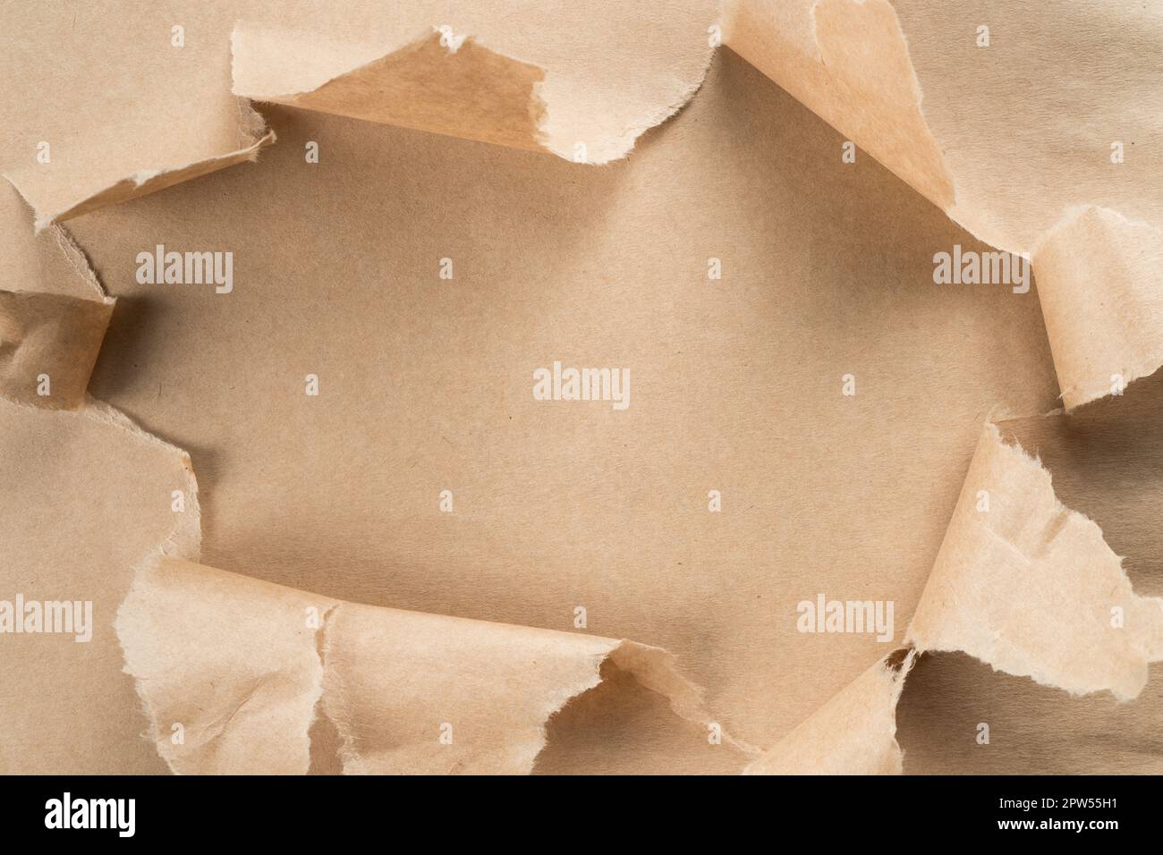 Beige crumpled packaging paper unwrapping from center, ragged paper ...