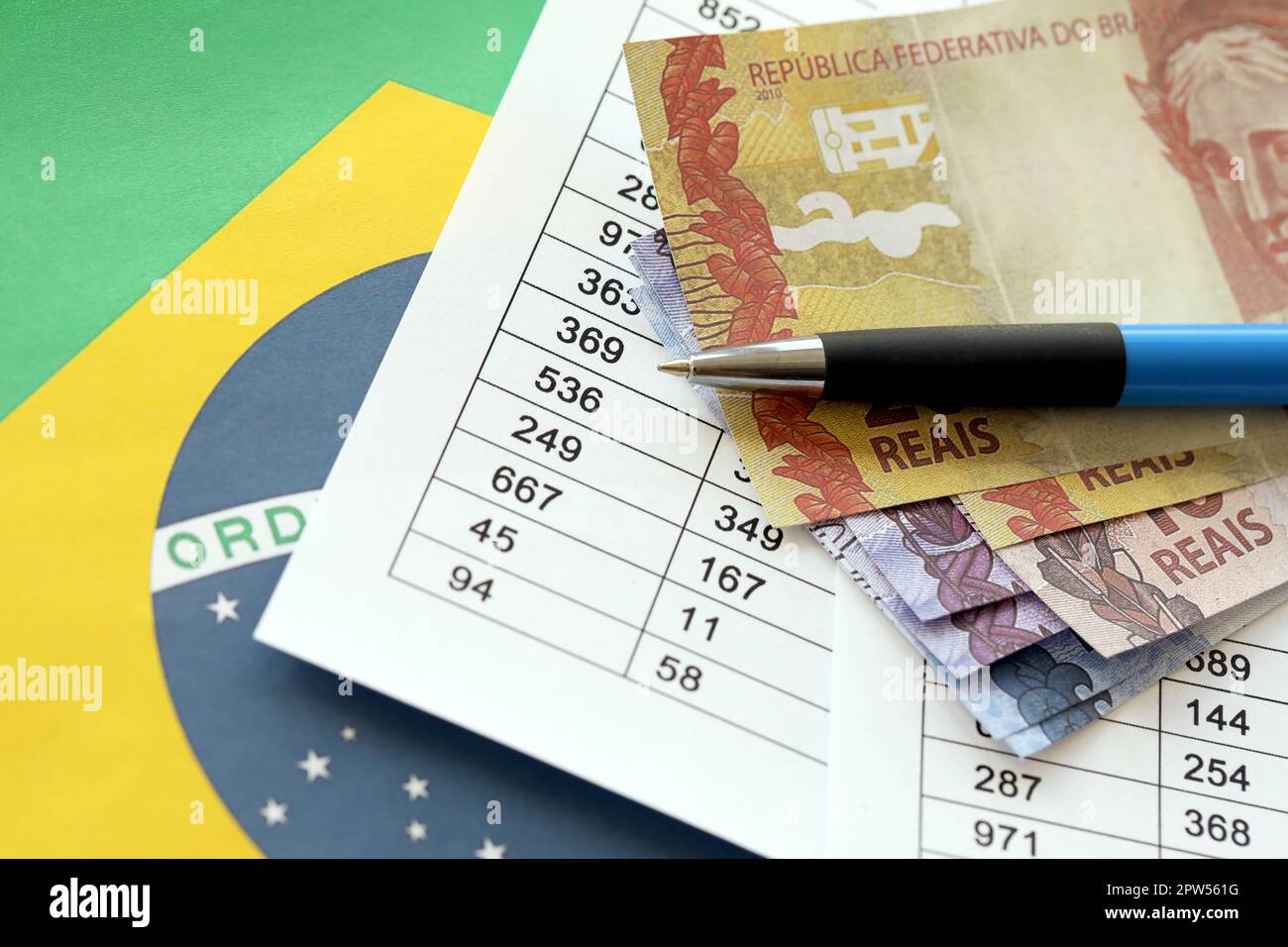 Pen with Brazilian money bills on flag of Brazil republic. Concept of ...