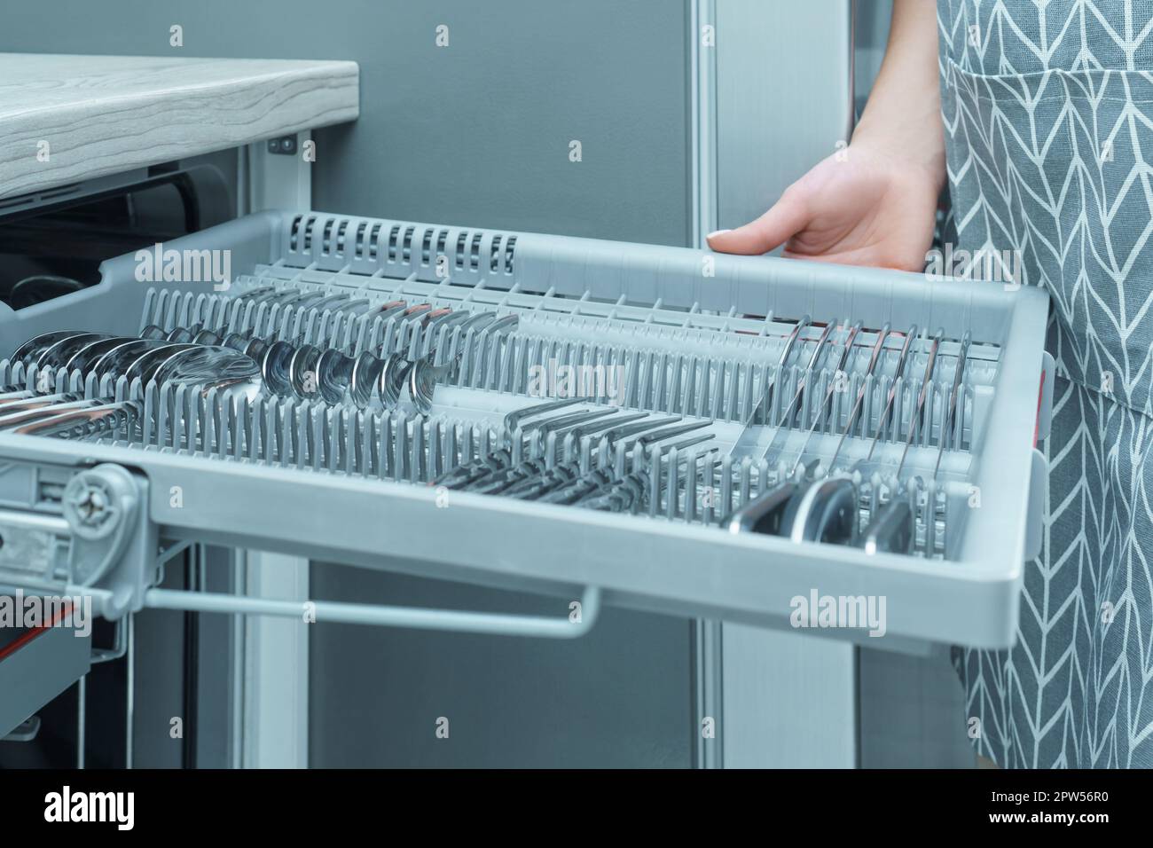 Human hand pull out shelf of dishwasher with clean sparkle cutlery ...