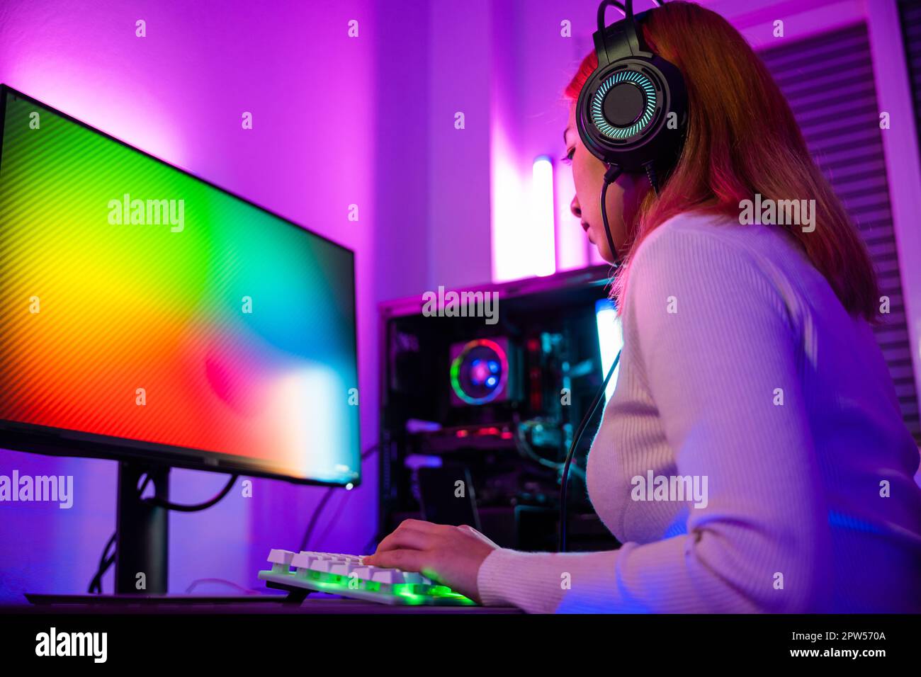 Asian woman gamer wearing gaming headphones holding joystick console to ...