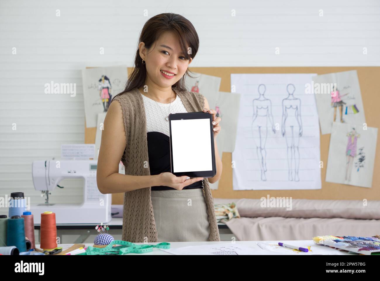 Fashion designer room. Young dressmaker with a smile showing blank ...