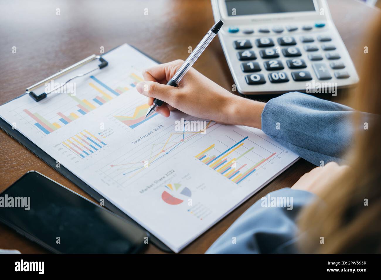 Woman accountant writing on business paper marketing statistic and data ...