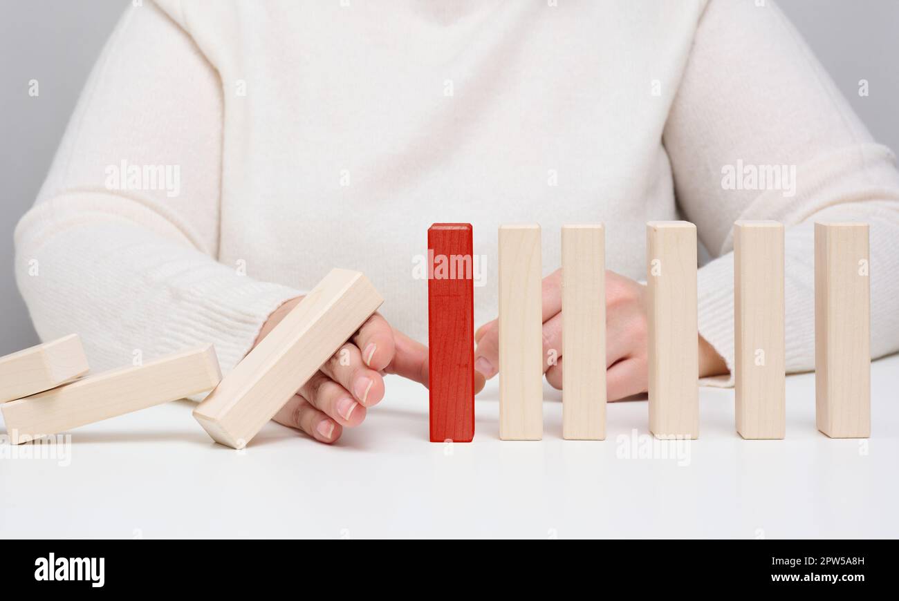 Hand stops the fall of wooden blocks on a white background. Concept of ...