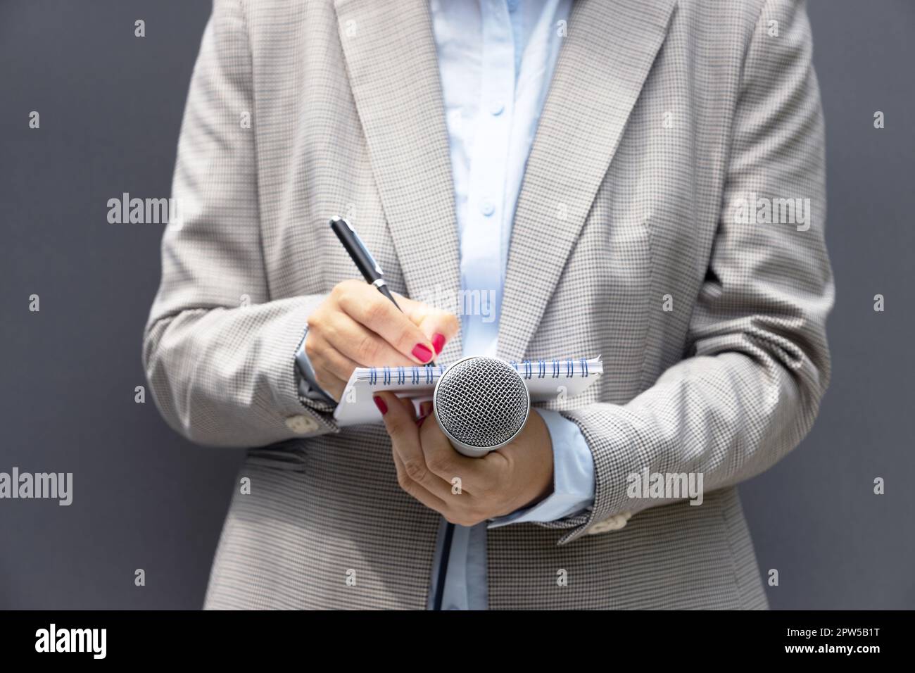 Reporter at press conference or media event, writing notes, holding ...