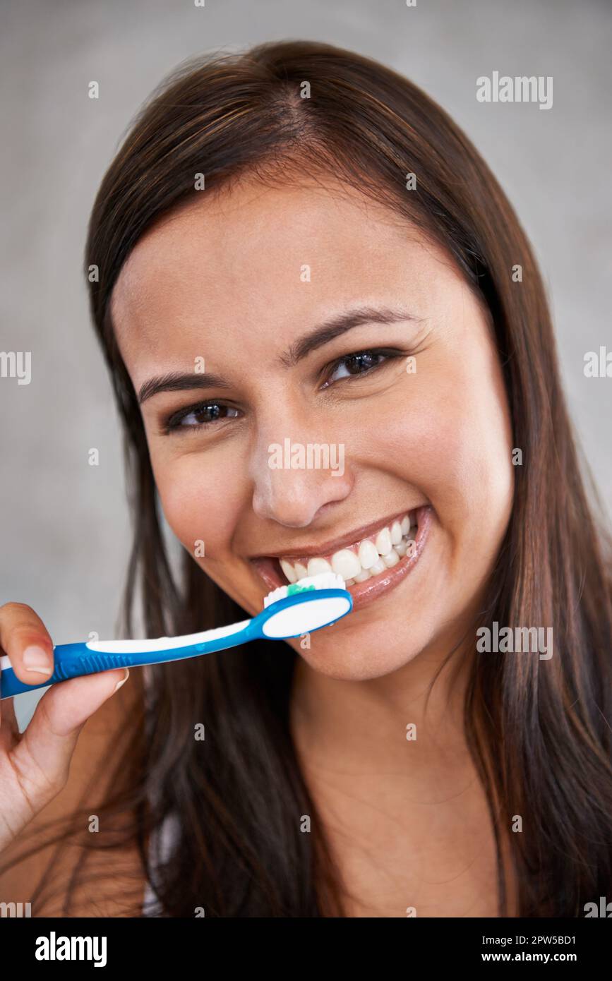 Brushing bad breath away. An isolated portrait of a young woman happily ...