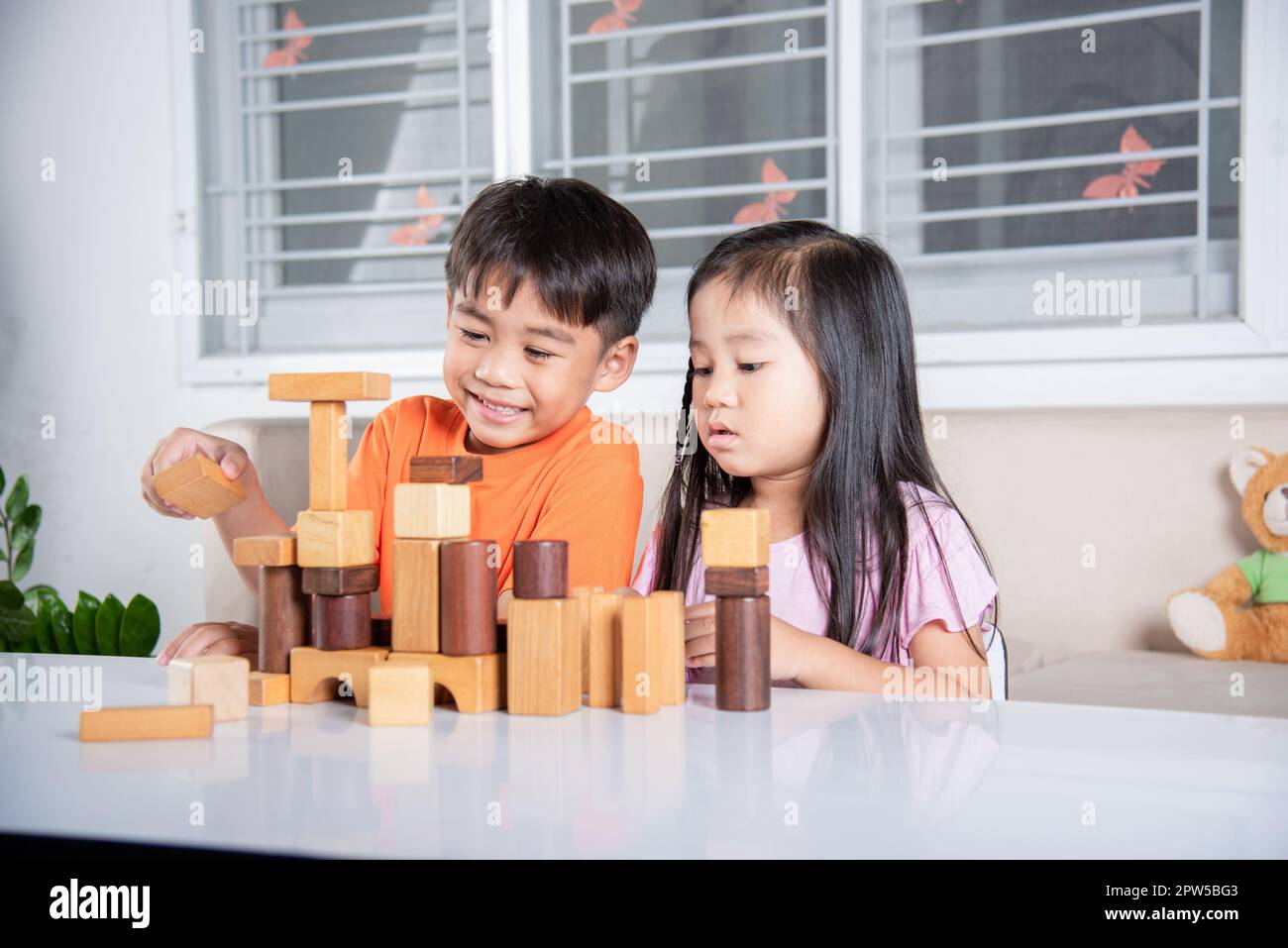 Children boy and girl playing with constructor wooden block building ...