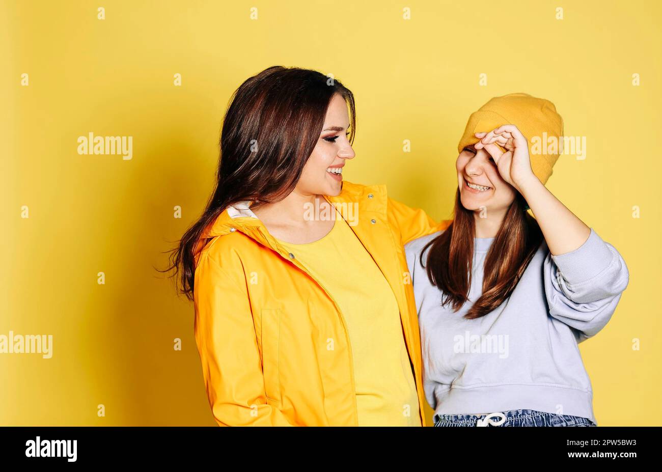 Two smiling cute female friends on the yellow background. Emotions ...