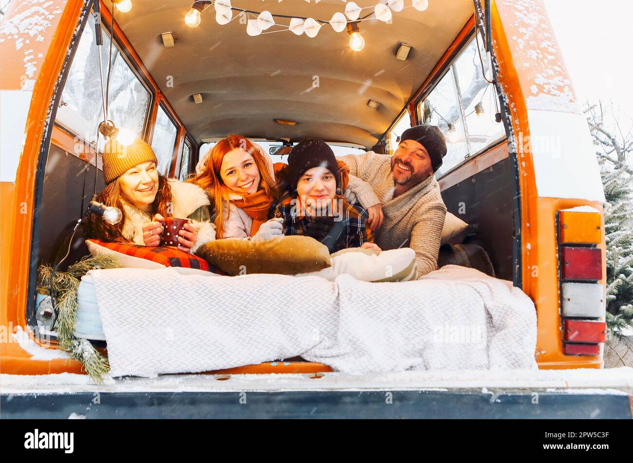 Happy family of travelers in minivan lying together at open rear doors ...