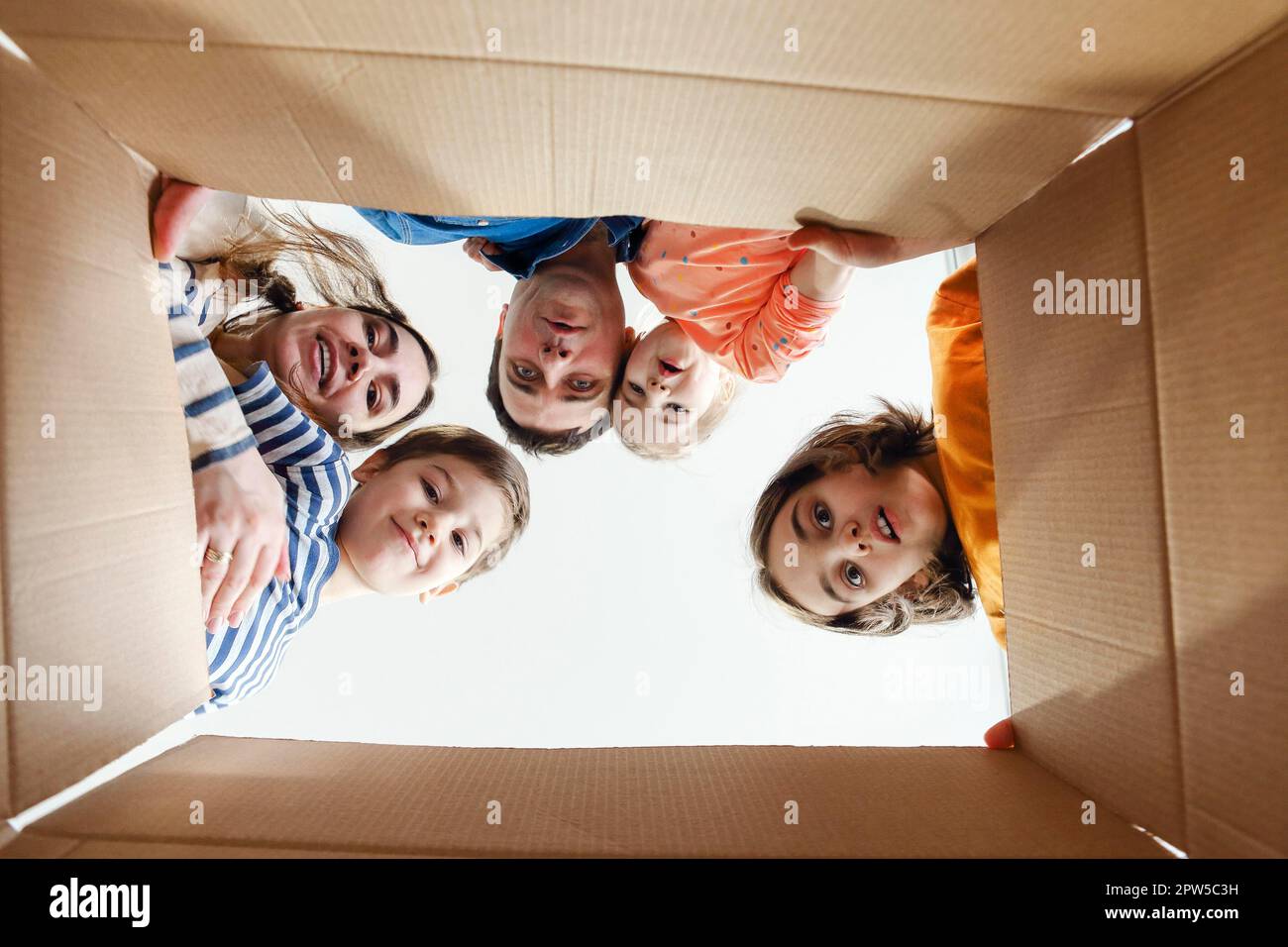 Happy family of five looking into cardboard box. Young family peeking ...