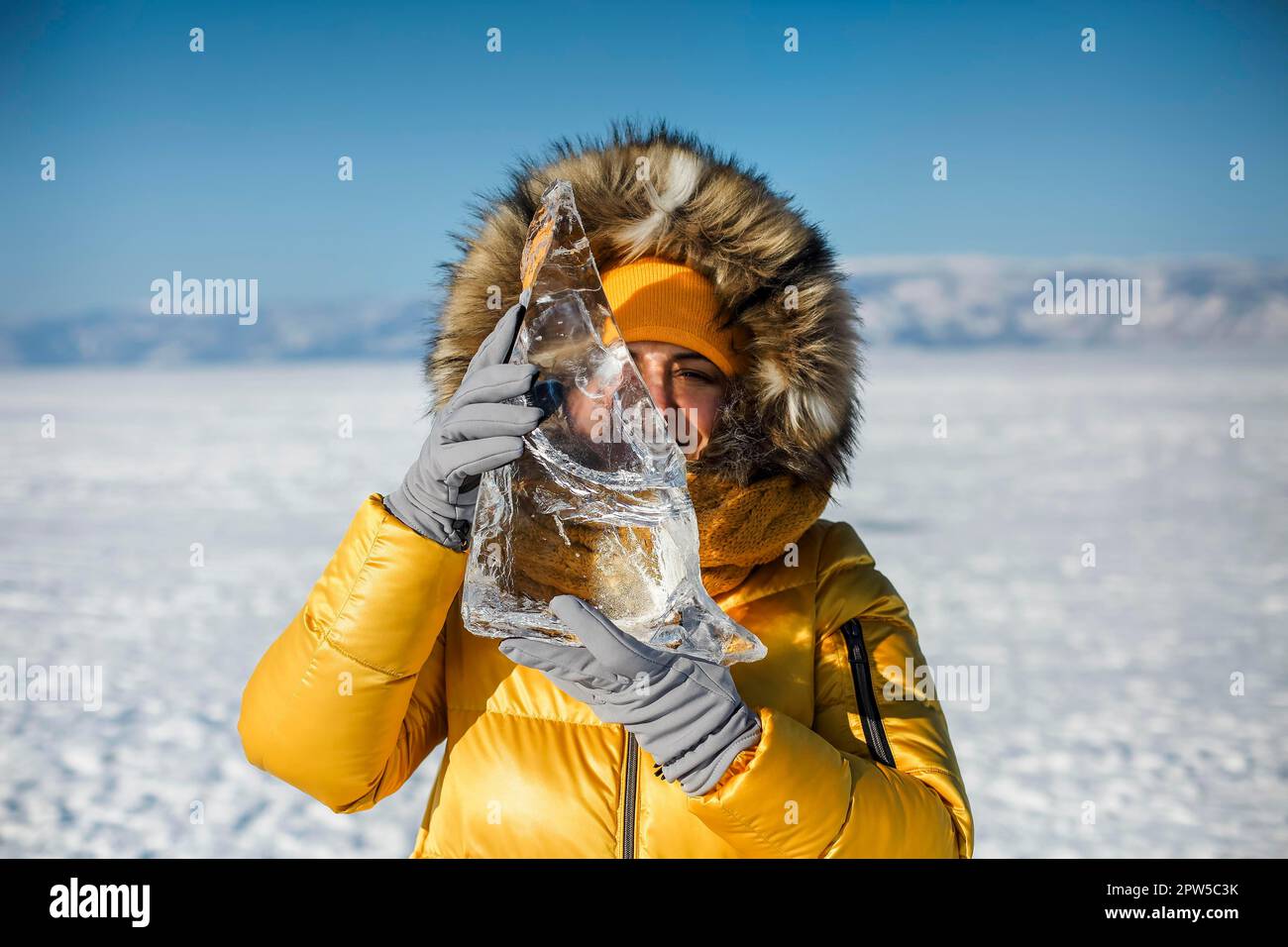 Happy smiling woman wearing winter yellow jacket holding piece of ...