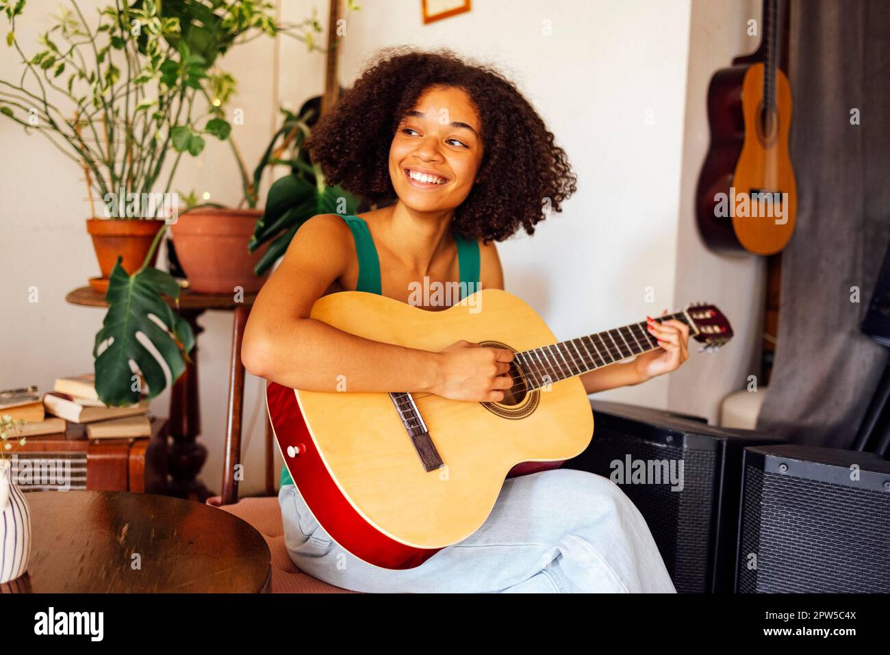 Smiling afro americal young woman playing acoustic guitar. Girl playing ...
