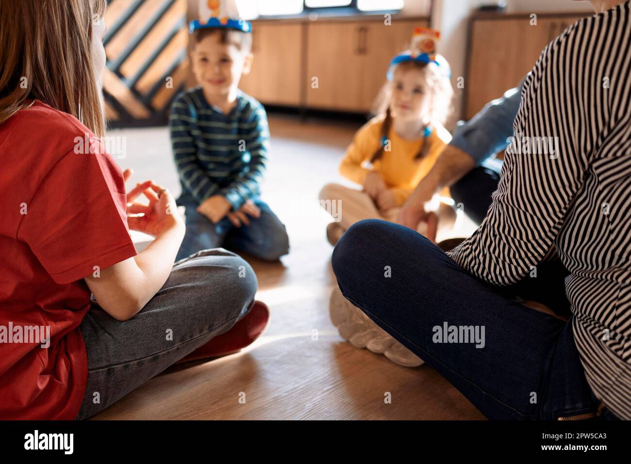 Happy young family with kids playing a card game at home sitting on the ...