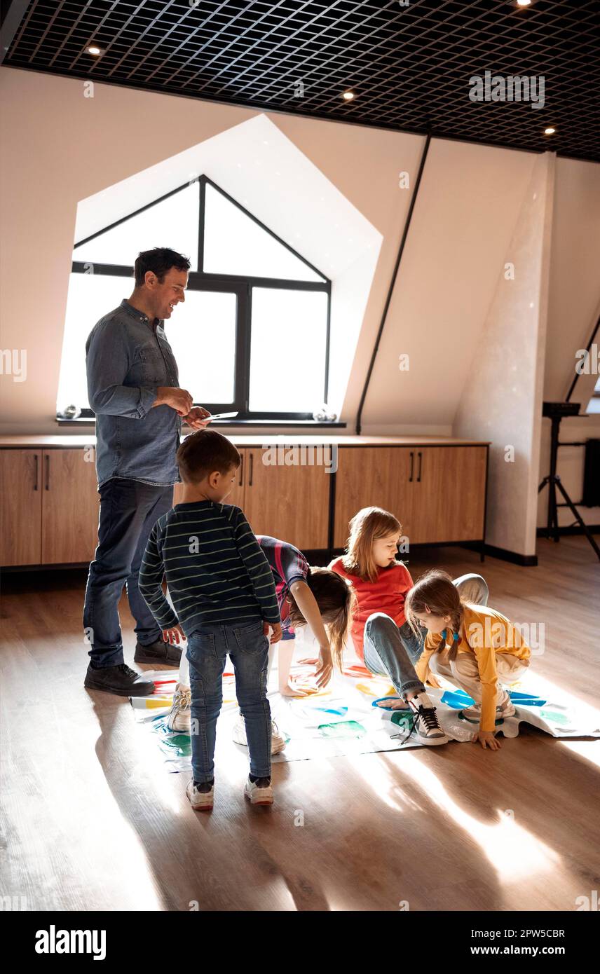 Happy big family having fun together, kids with father playing twister ...
