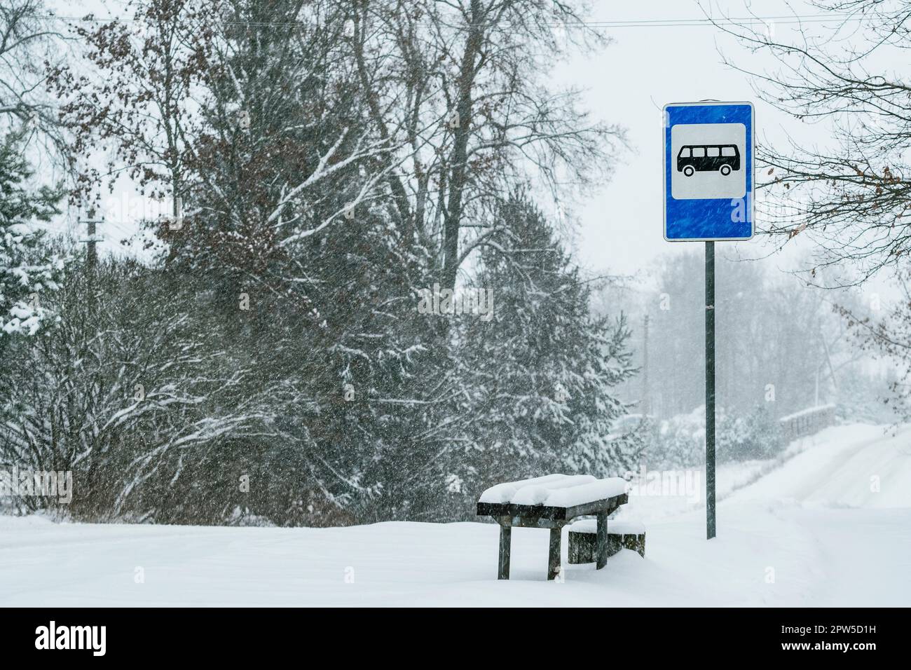 Empty bus stop on a winter road in a blizzard. Traffic and vehicles in ...