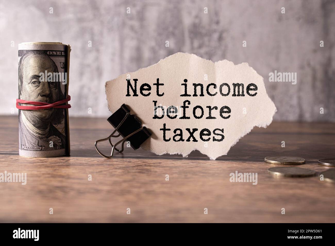 Net Income Before Taxes, text on white paper on torn paper background ...