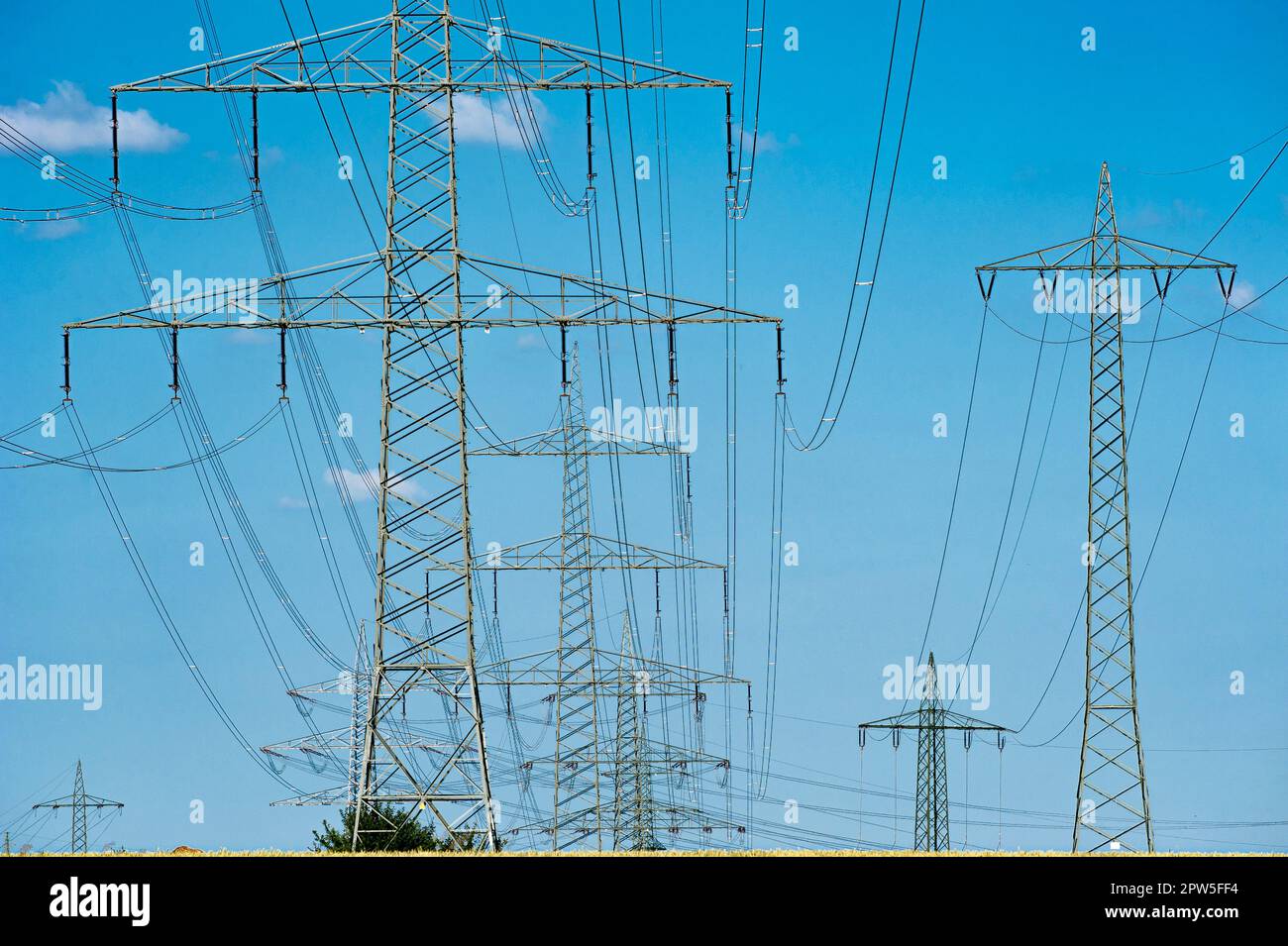 High voltage pylons with overhead lines against blue sky Stock Photo ...