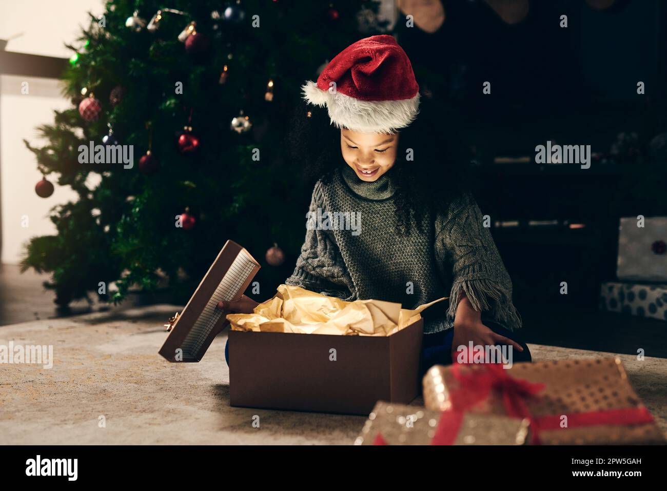 Christmas, gift and girl opening box at night in home on holiday. Xmas ...