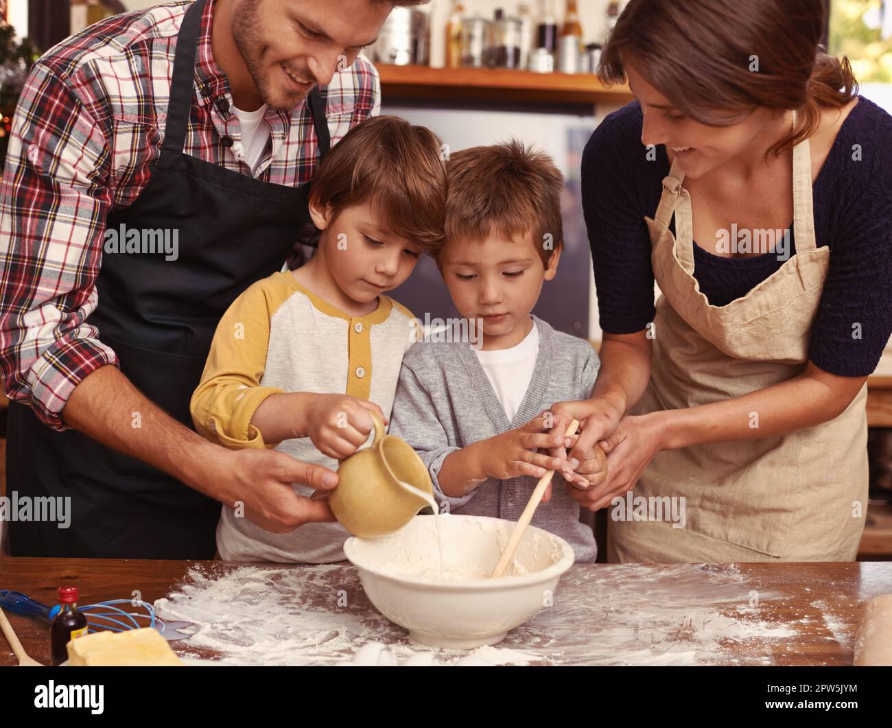 Baking as a family. Two cute little boys baking with their parents in ...