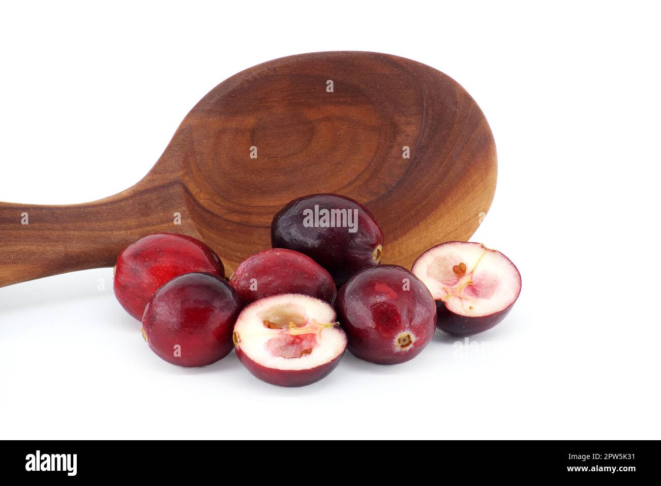 Fresh cranberries and cranberry berry cut in half in front of wooden ...
