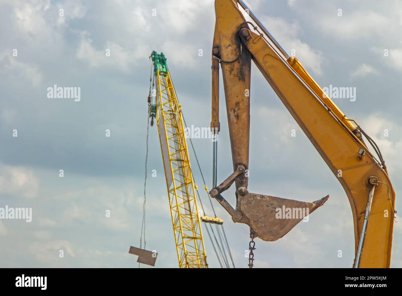 Yellow backhoe working riverside and on the roadside Stock Photo - Alamy