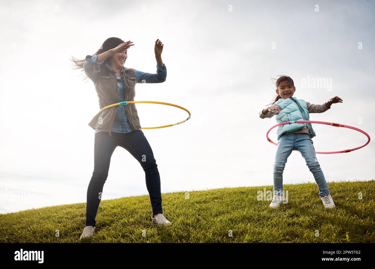 Spinning on the double. a little girl and her mom having a hula hoop ...