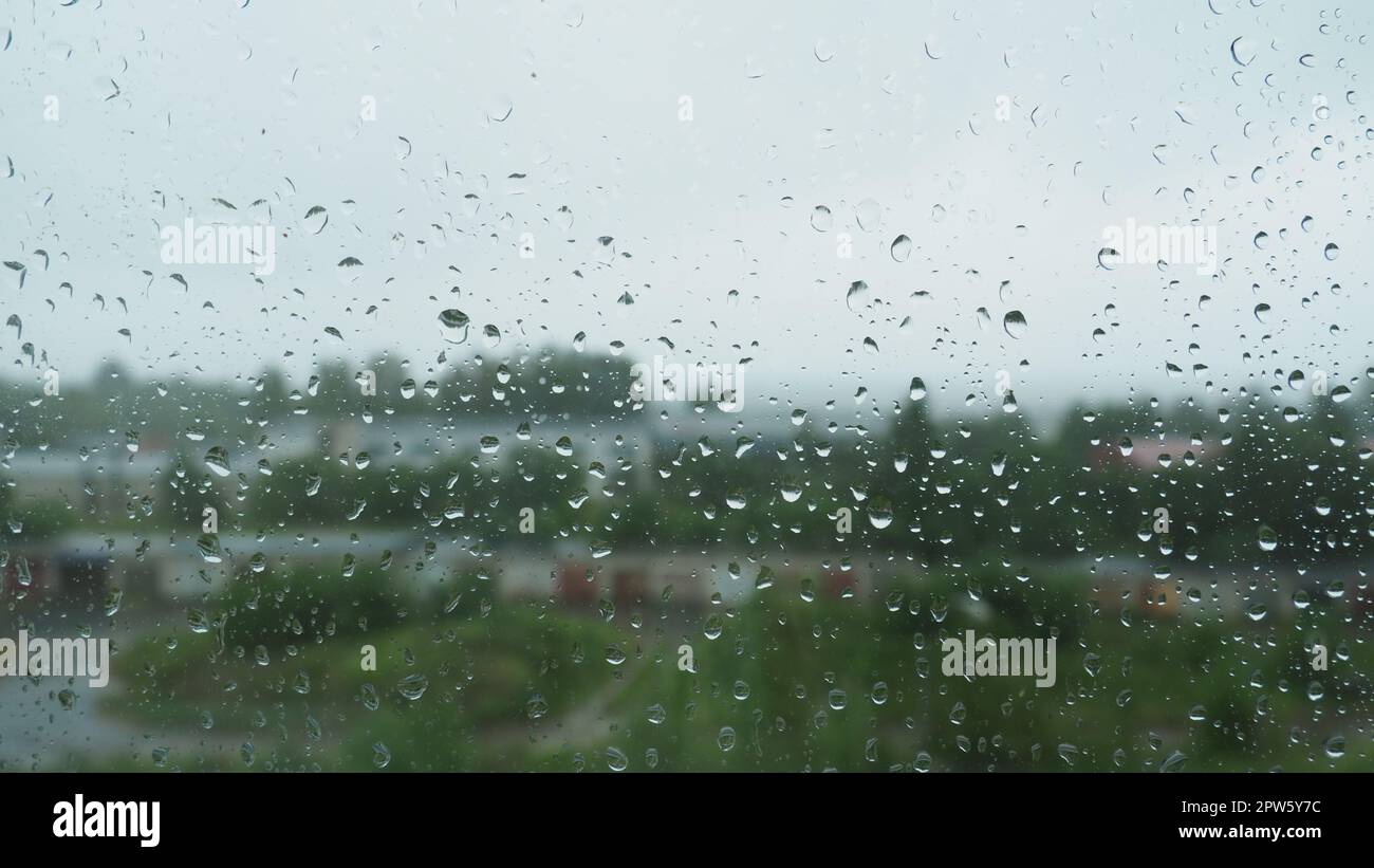 Raindrops on the glass window on a rainy day. Water drips from above ...