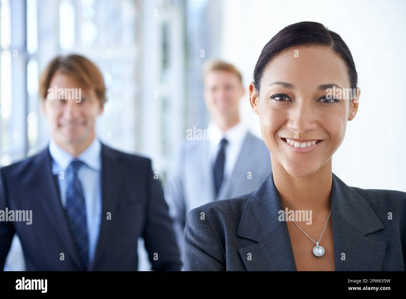 Shes Breaking The Glass Ceiling With Ease A Smiling Businesswoman With Two Coworkers Behind Her