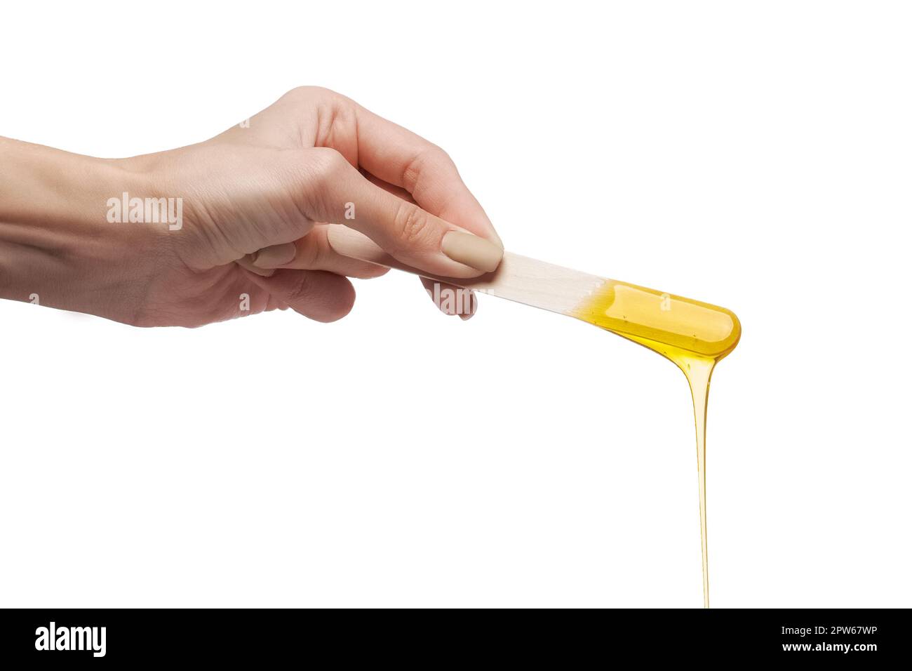 Hand holding beauty wax on wooden spatula flowing down Stock Photo - Alamy